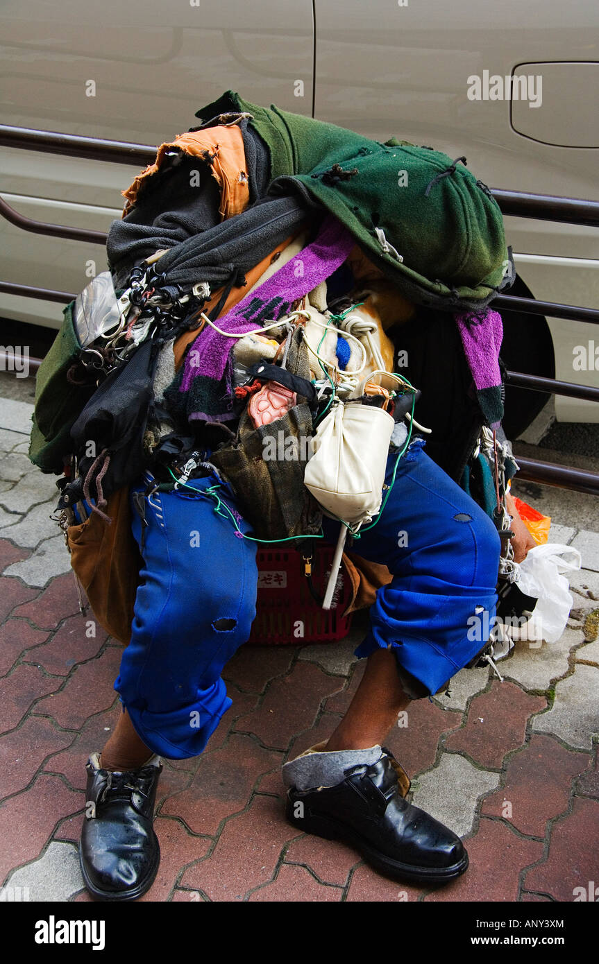 Japan, Honshu Island, Tokyo, Ginza District. Homeless tramp slumped in ...