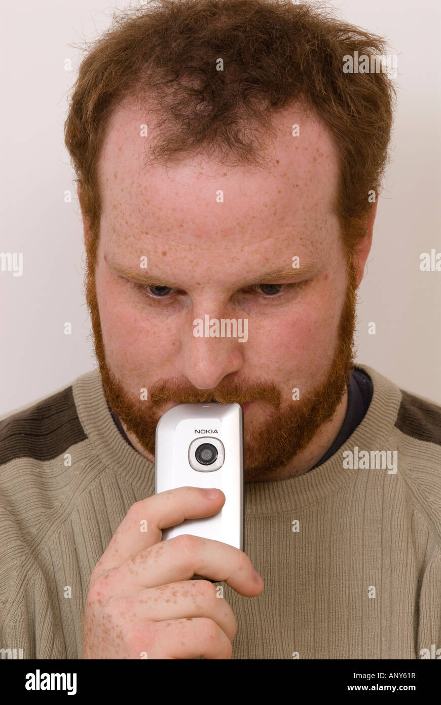 man looking at mobile phone with a concerned worried look on his face ...