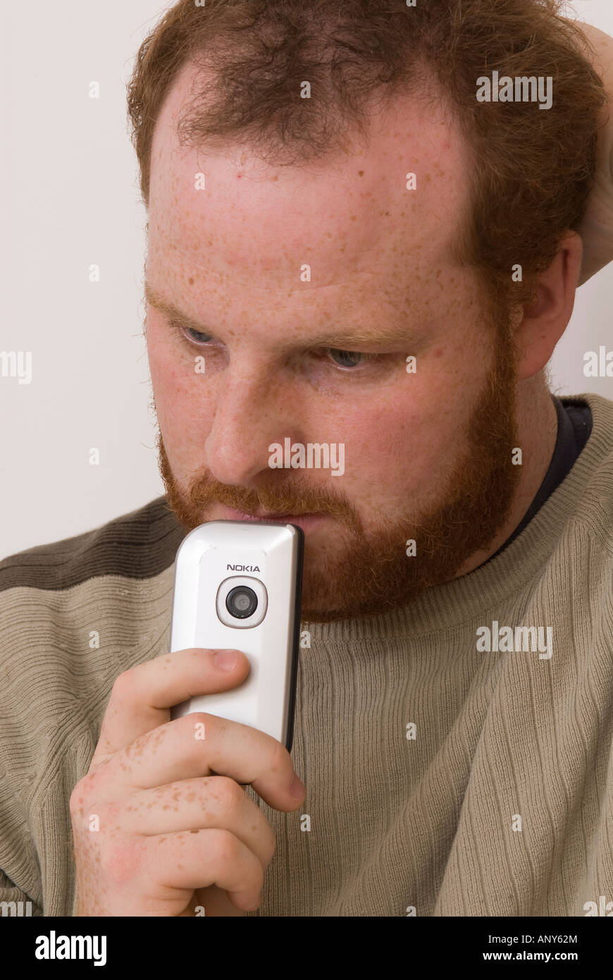 man looking at mobile phone with a concerned worried look on his face ...