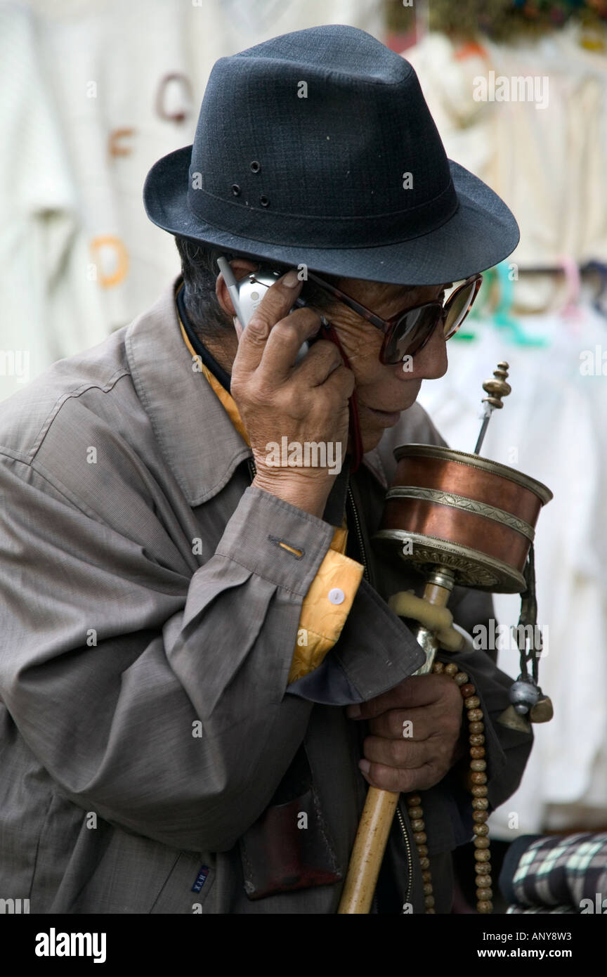 Pilgrim with a mobile phone in one hand and a prayer wheel in the other ...