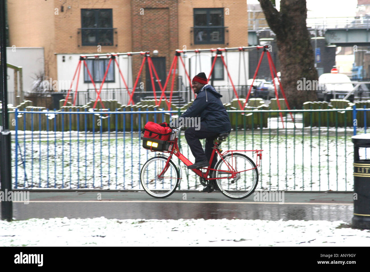Black postman rdiing red bike in the snow Stock Photo - Alamy
