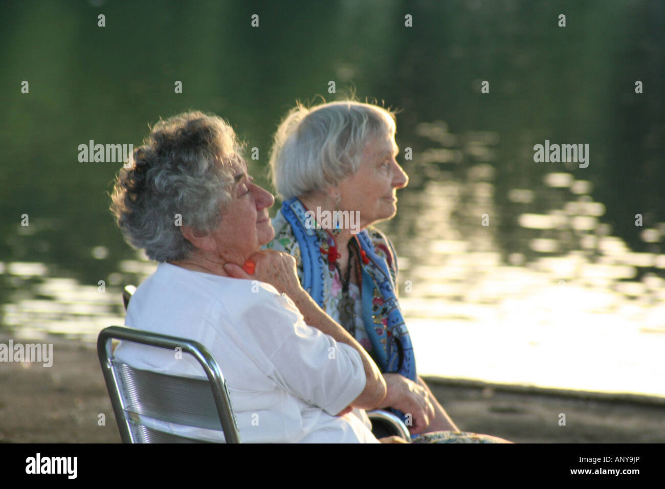 2 elderly ladies sit on chairs by a park pake in Summer Stock Photo - Alamy