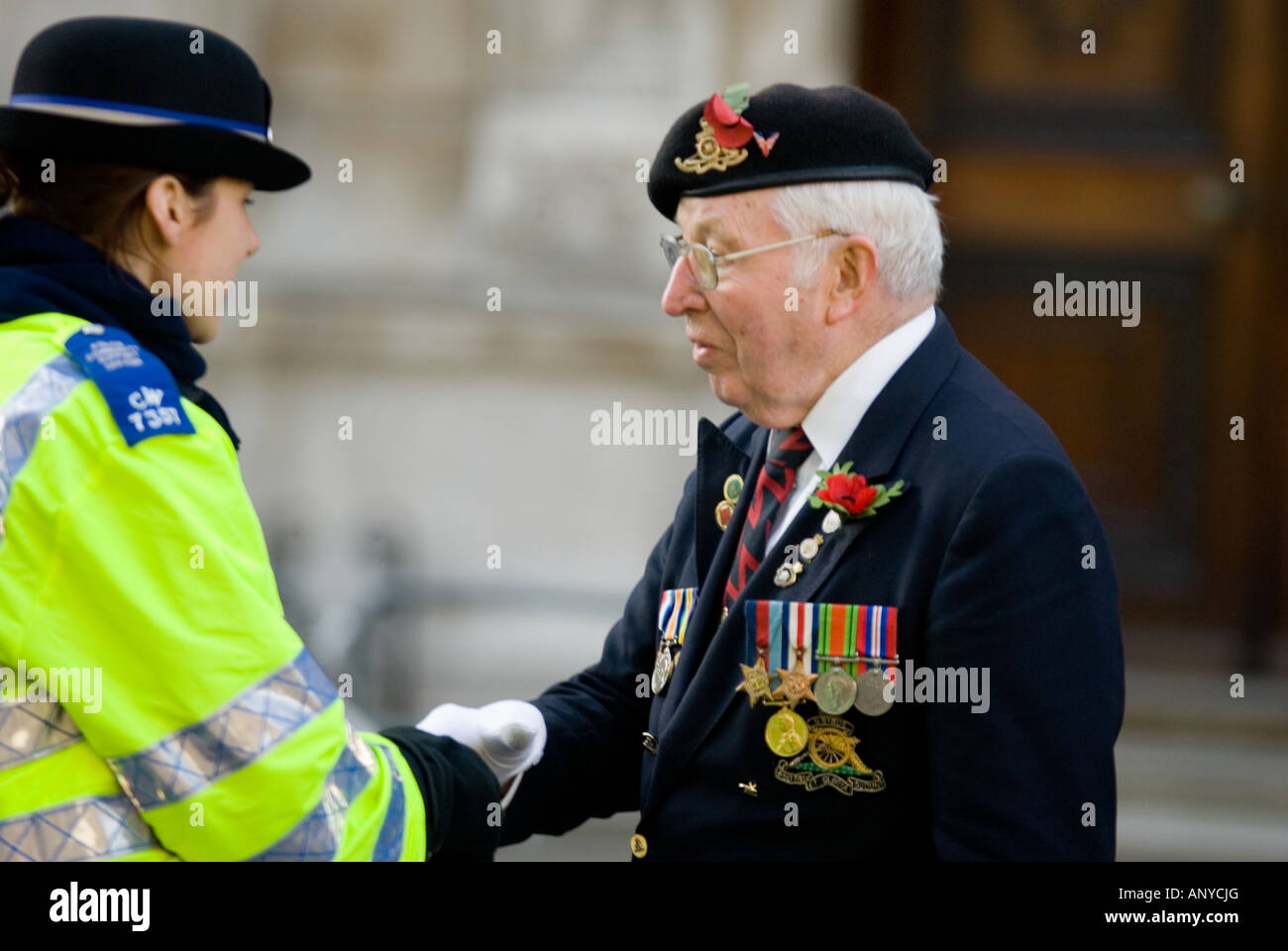 old veteran man with medals shake hands to a police woman to ...