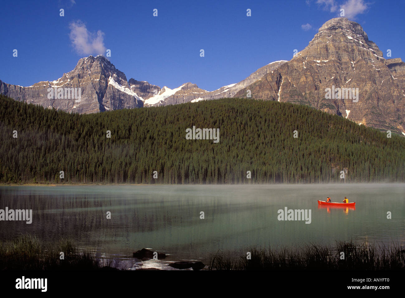 Alberta, Banff National Park, Boys fishing from a red canoe in ...