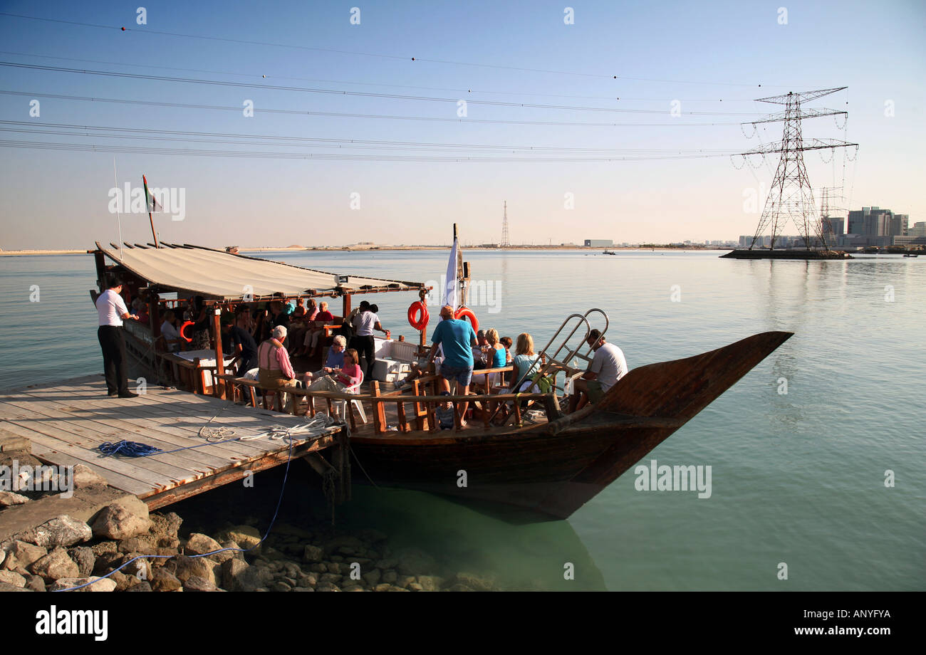 A traditional wooden dhow moored and taking on passengers for a ...