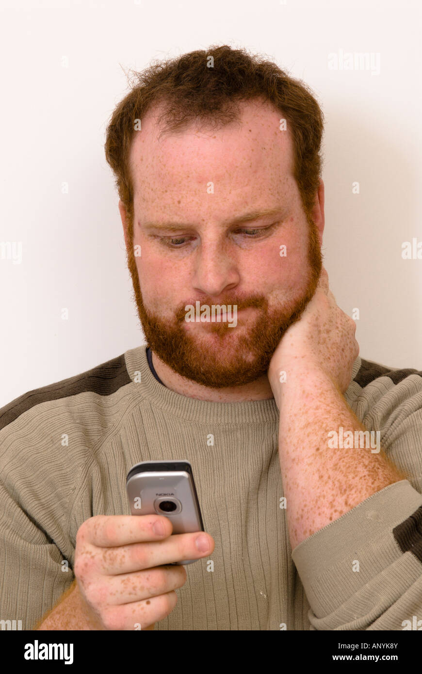 man looking at mobile phone with a concerned worried look on his face ...