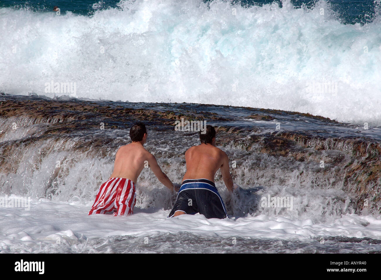 Two man hiding behind a rock Stock Photo - Alamy