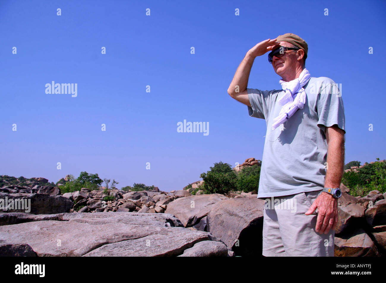 man looking into the distance with hand protecting from the sun light ...