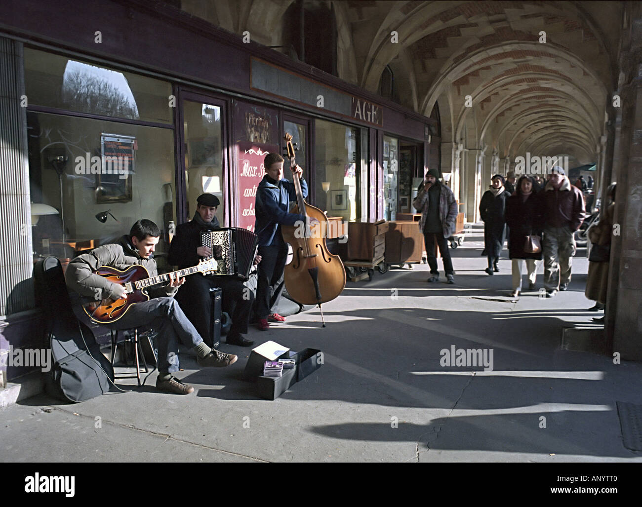 A band performs for tourists and passers-by under the Place des Vosges ...
