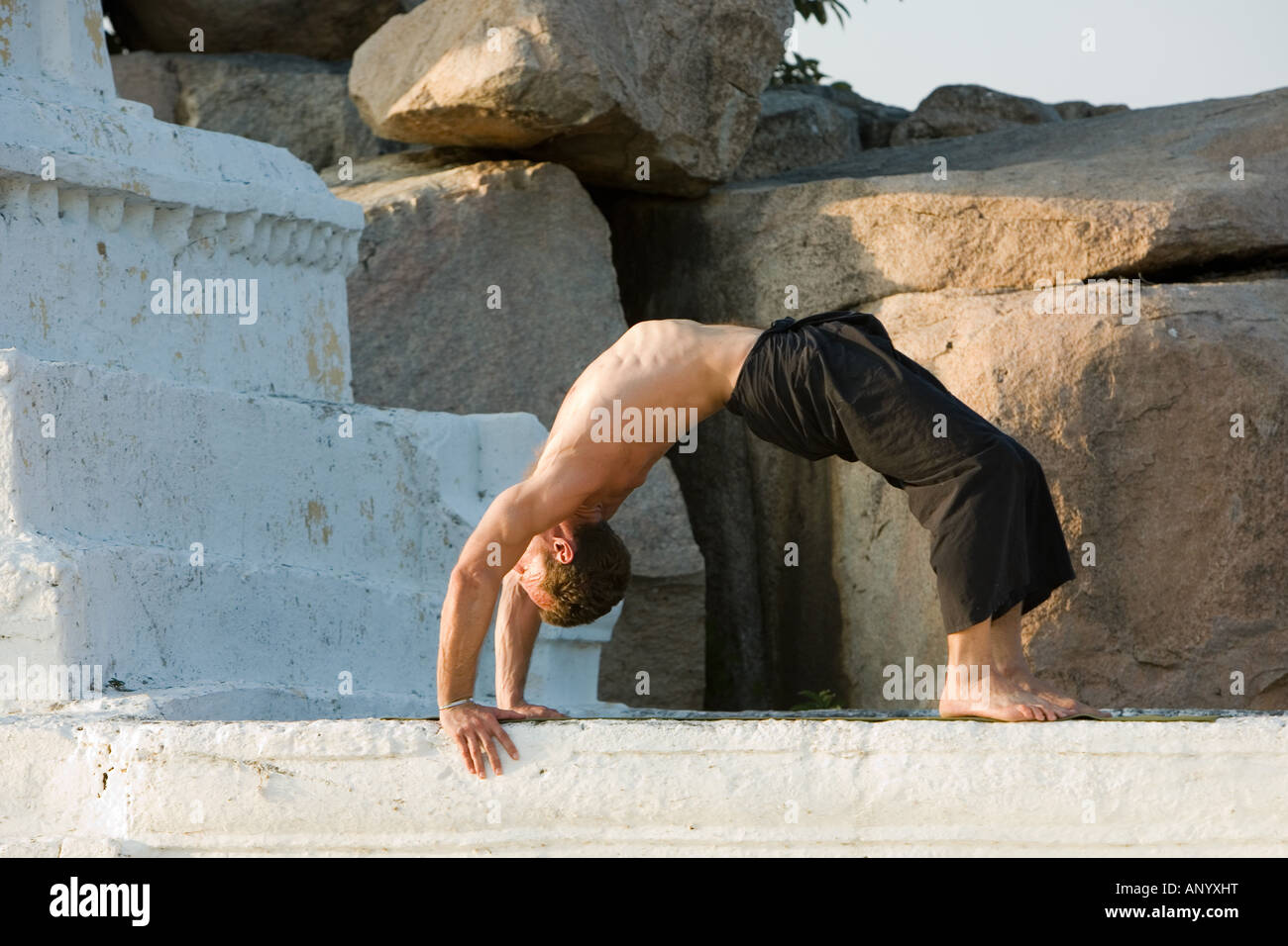 Man performing Hatha Yoga, Urdhva Dhanurasana, wheel posture on a hindu ...