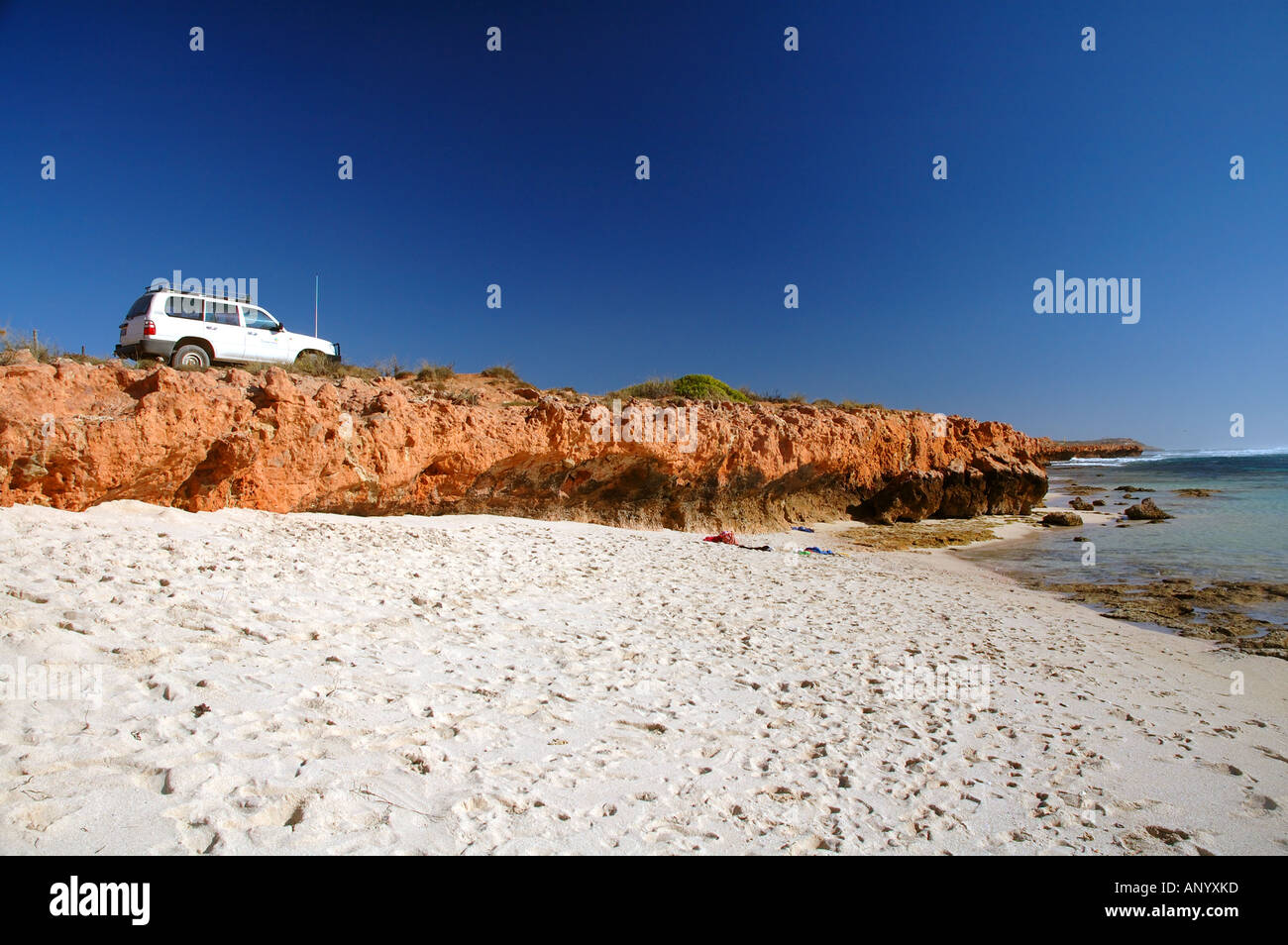 4WD vehicle parked on red rocks next to beach 3 Mile Sanctuary Zone ...