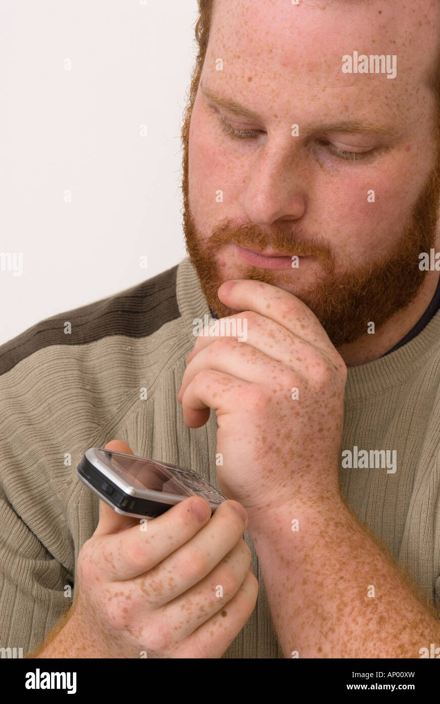 man looking at mobile phone with a concerned worried look on his face ...