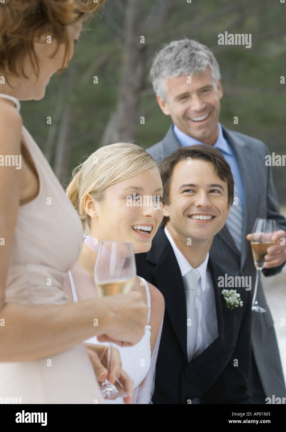 Outdoor wedding party, young bride and grooming standing between mature ...