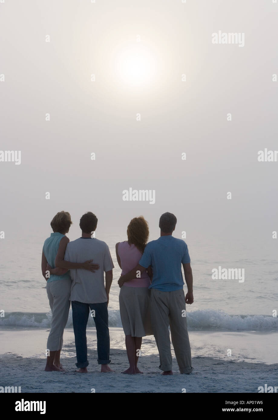 Two couples standing on beach at twilight, rear view Stock Photo - Alamy