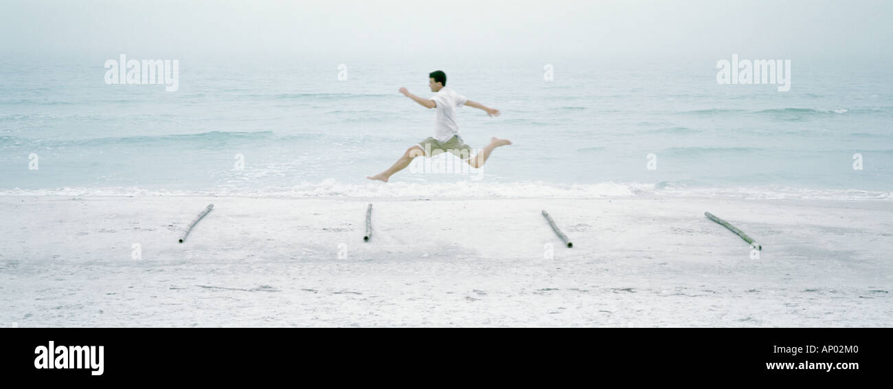 Man running and jumping over logs on beach Stock Photo - Alamy
