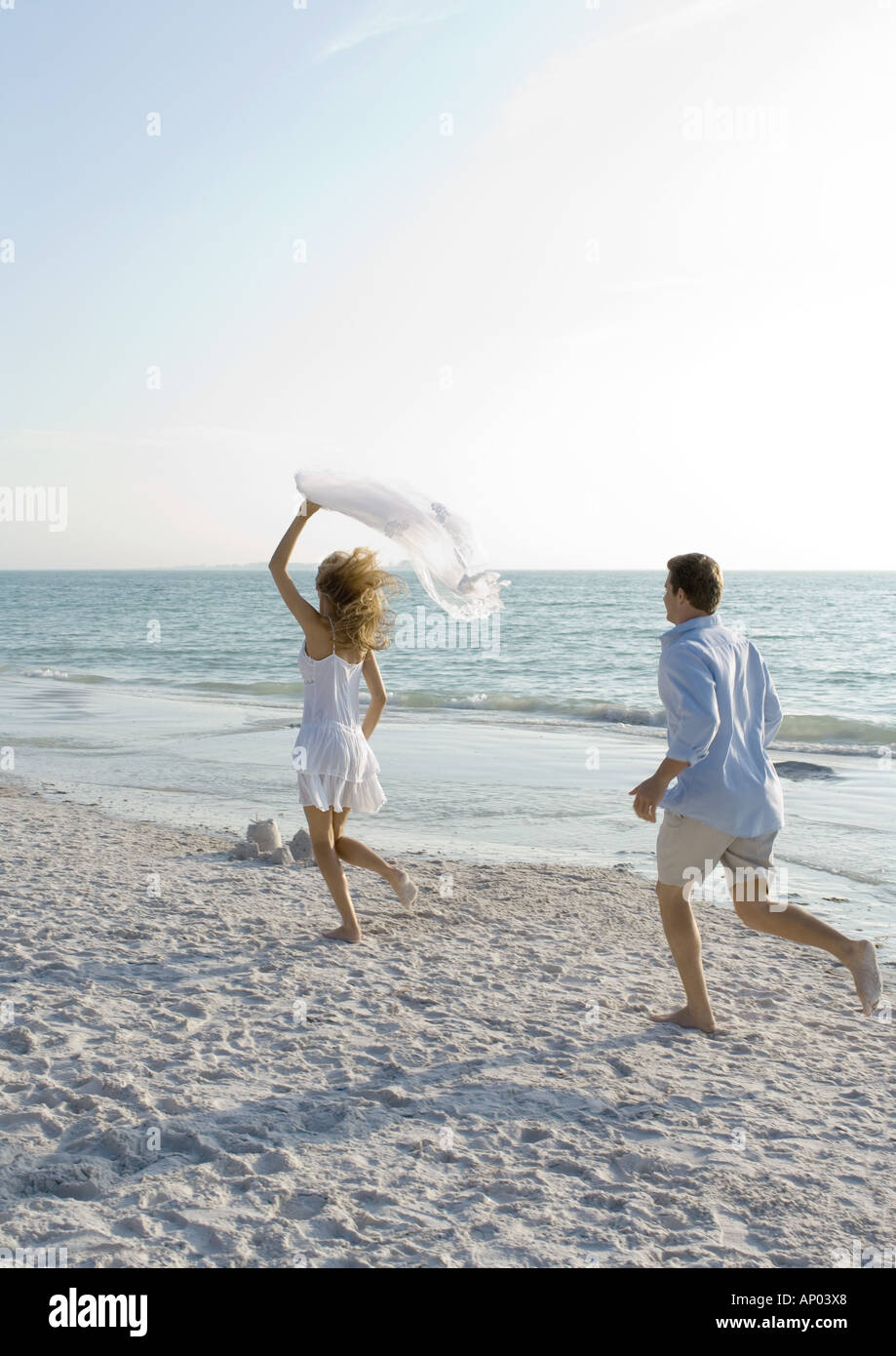 Newlyweds, man chasing woman on beach Stock Photo - Alamy