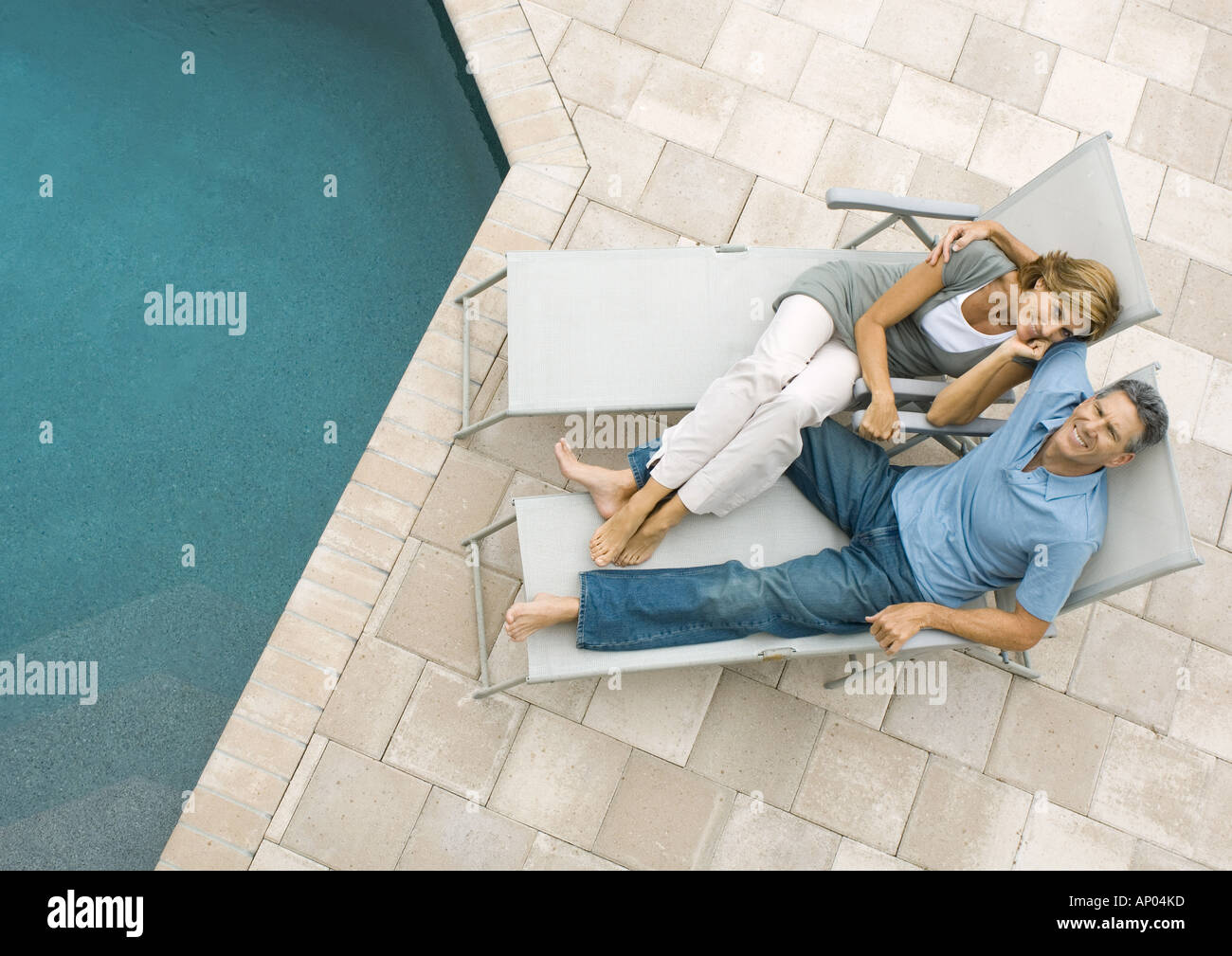 Mature couple lounging by pool Stock Photo - Alamy