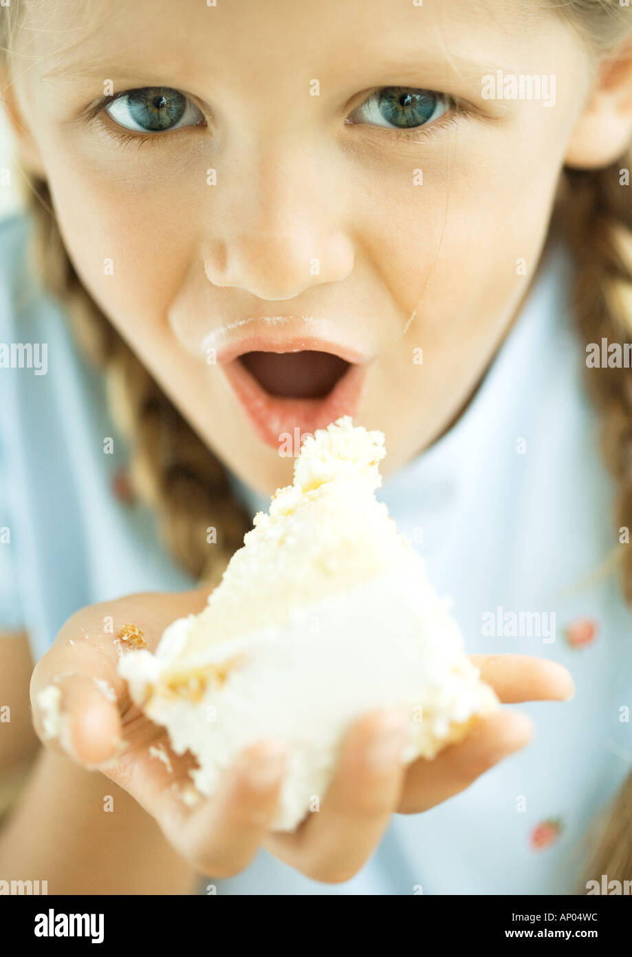 Girl eating piece of cake with hand Stock Photo - Alamy