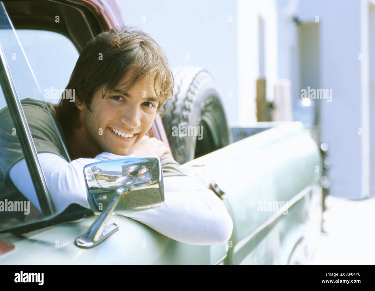Young man in car, leaning on edge of car window frame Stock Photo - Alamy