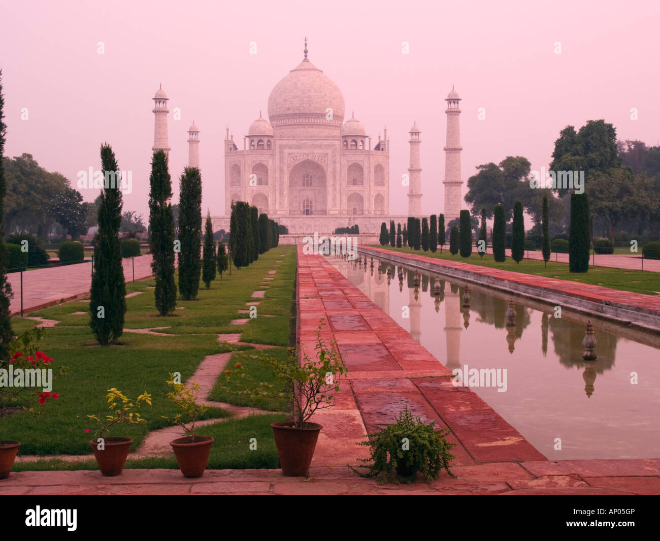Taj Mahal mausoleum in pink glow of early morning light with in water ...