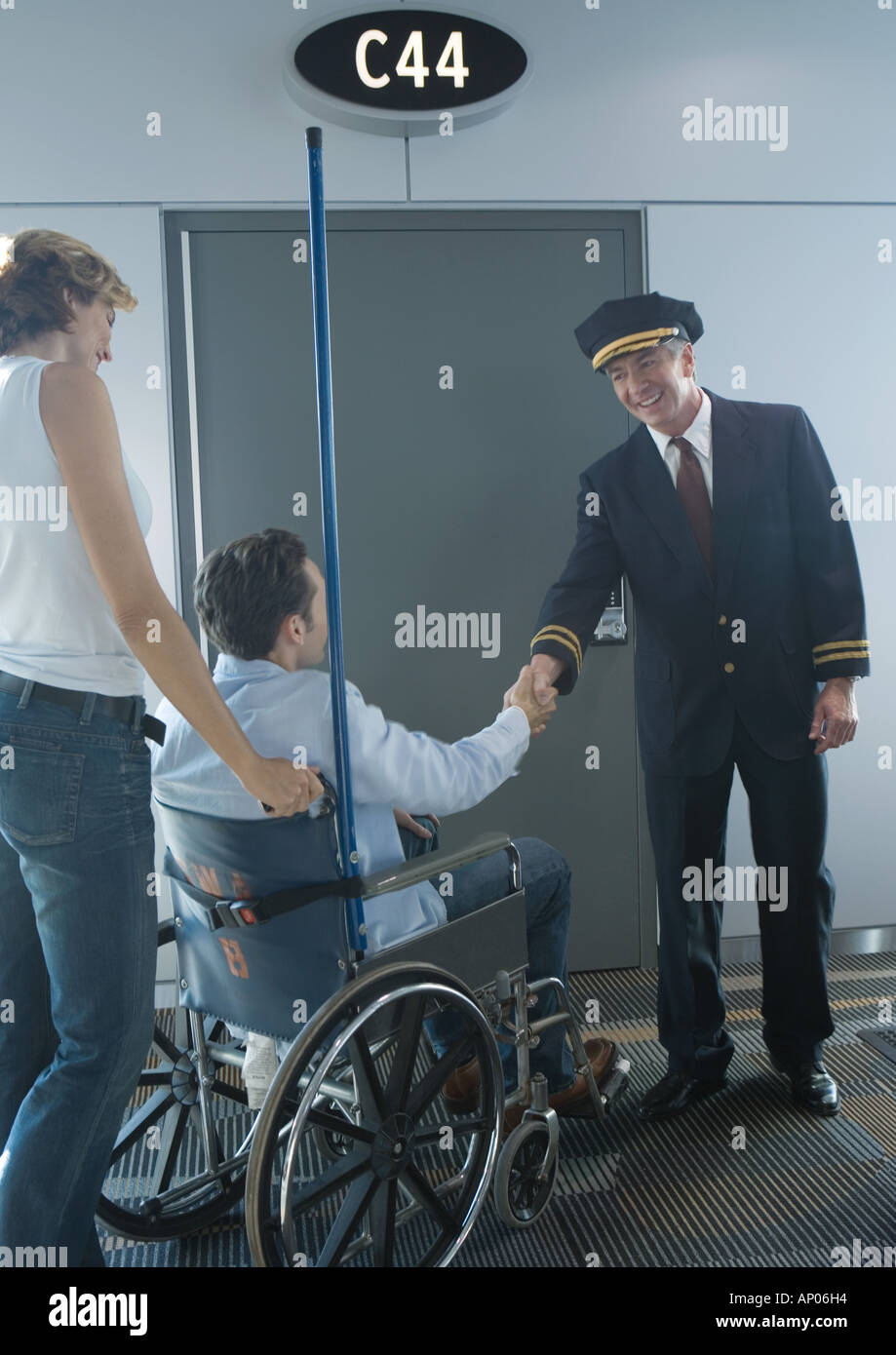 Man in wheelchair shaking hands with pilot in airport Stock Photo - Alamy