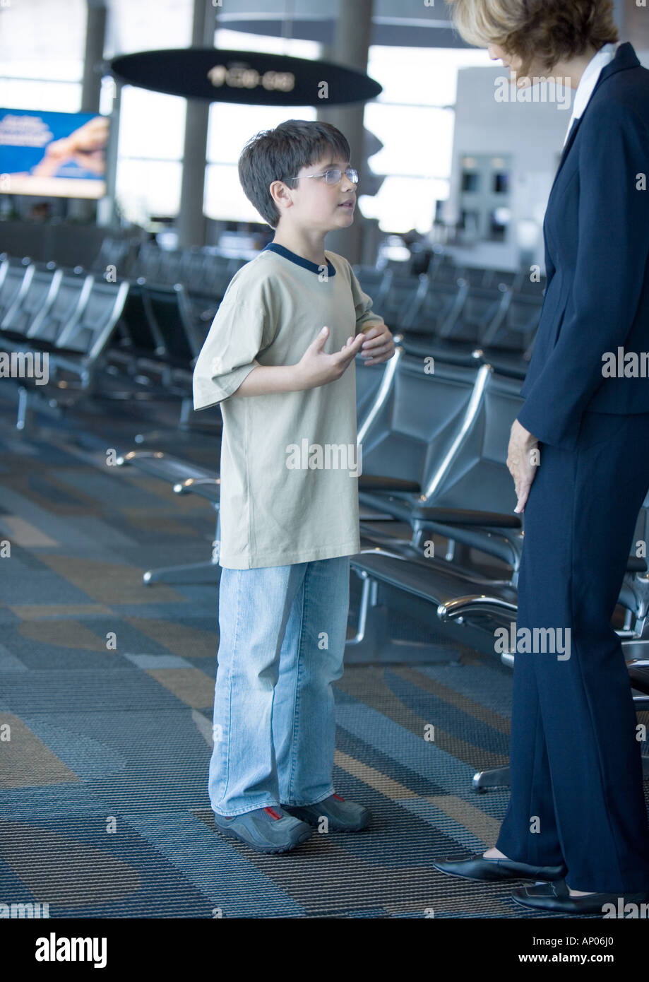 Boy speaking to airline attendant in airport lounge Stock Photo - Alamy