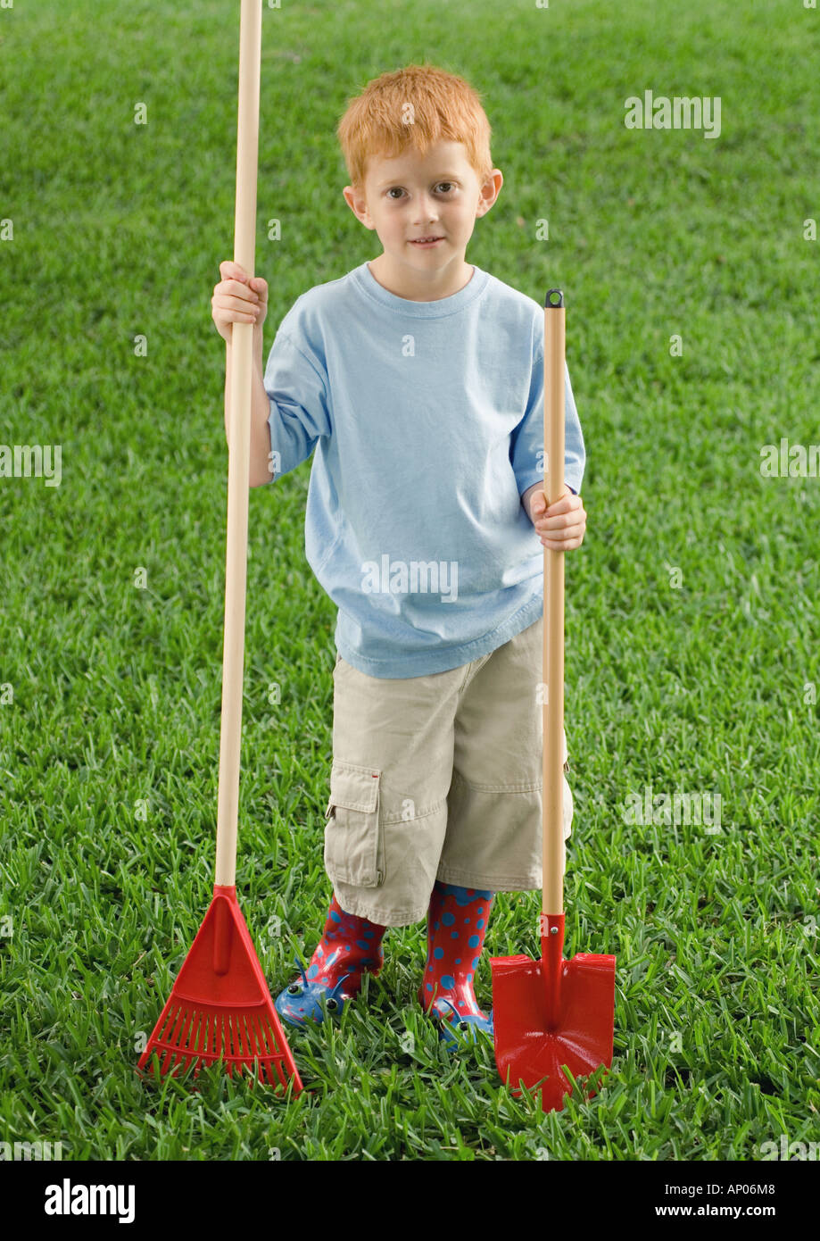 Boy standing with rake and shovel, portrait Stock Photo - Alamy
