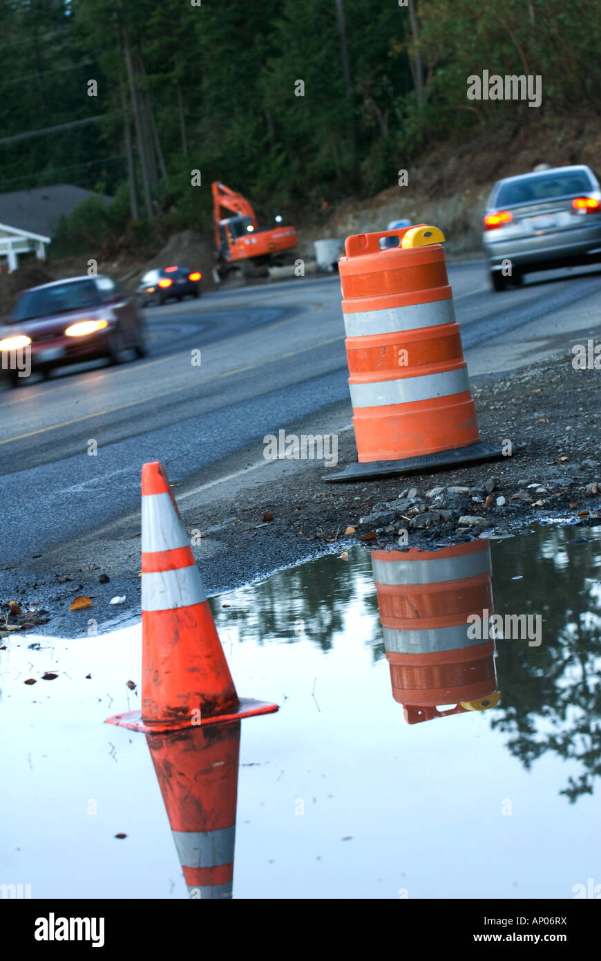 traffic cones reflected in water along street during road construction ...