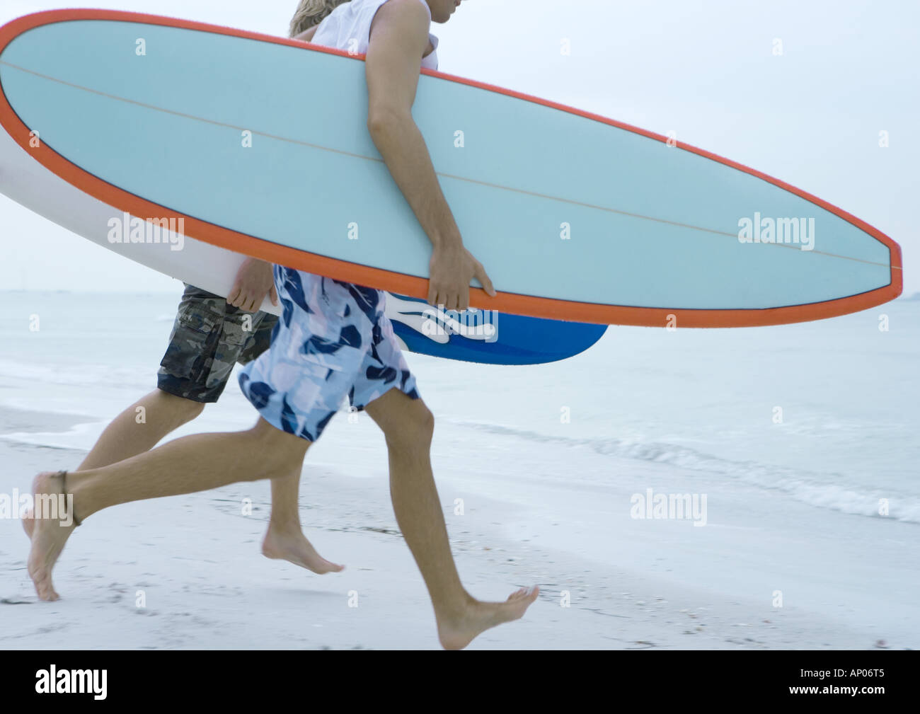 Young men running with surfboards Stock Photo - Alamy