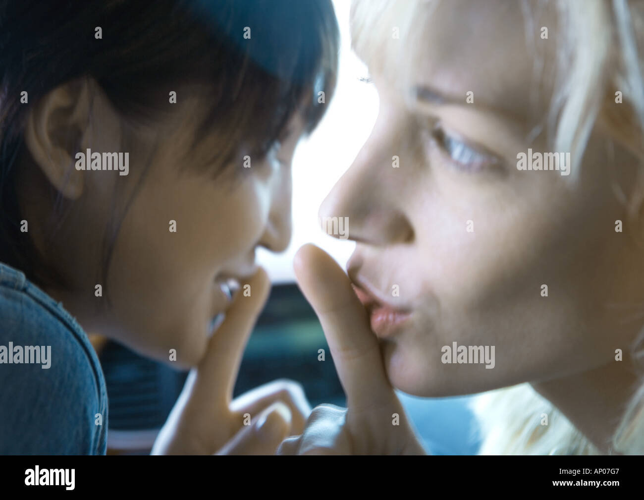 Two young women holding fingers to lips Stock Photo - Alamy