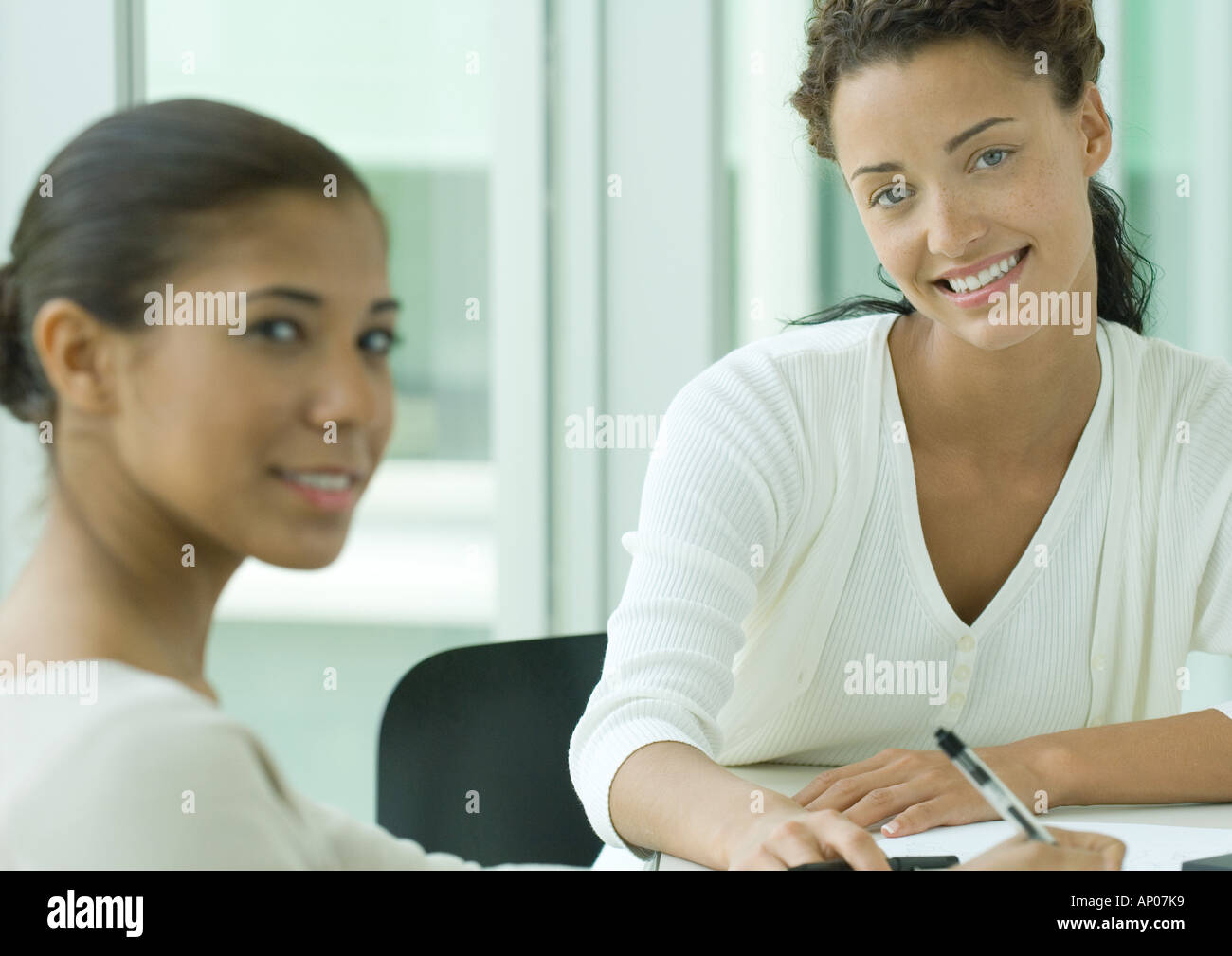 Two female coworkers, smiling at camera Stock Photo - Alamy