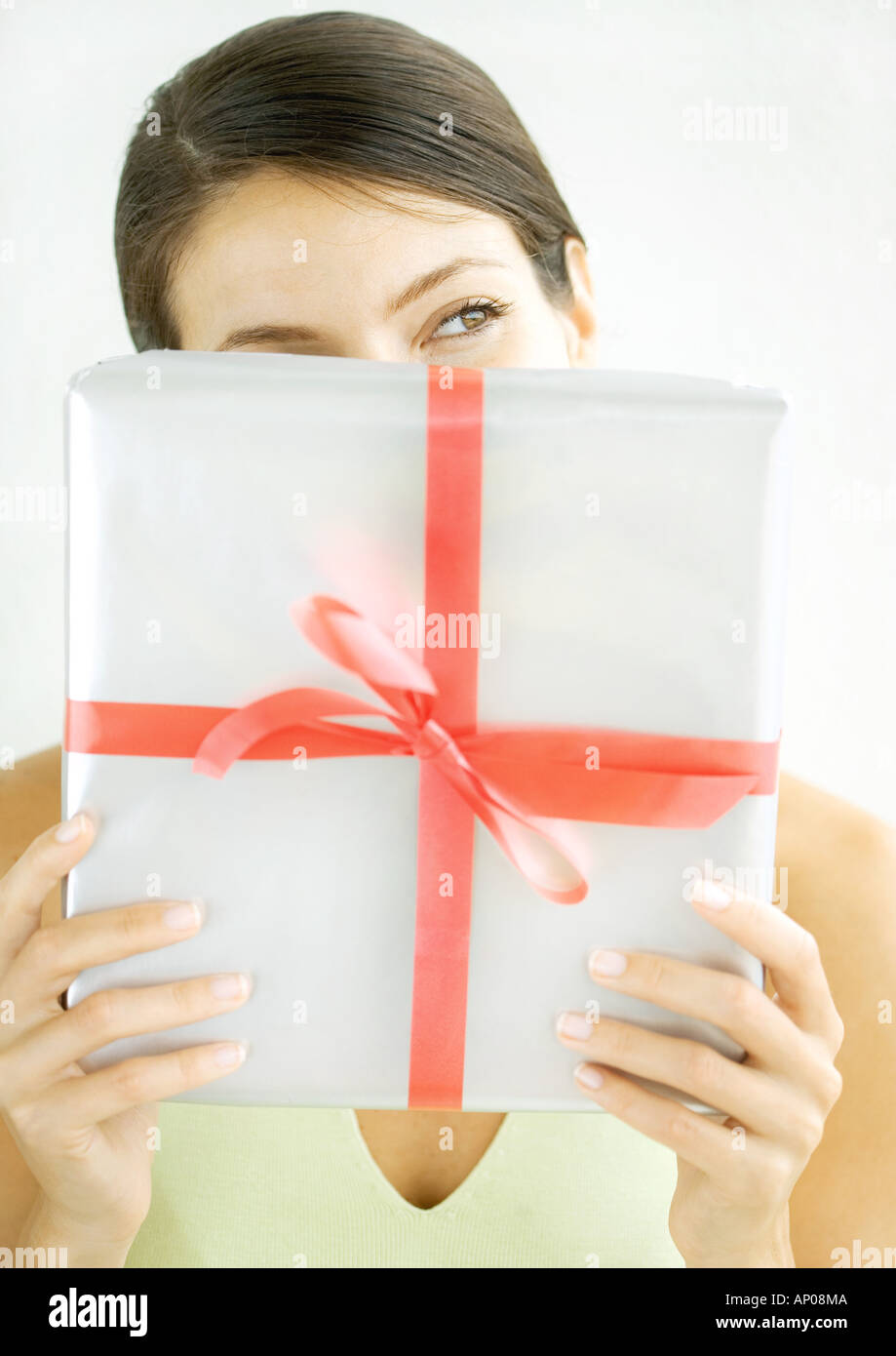 Woman holding present in front of face Stock Photo - Alamy