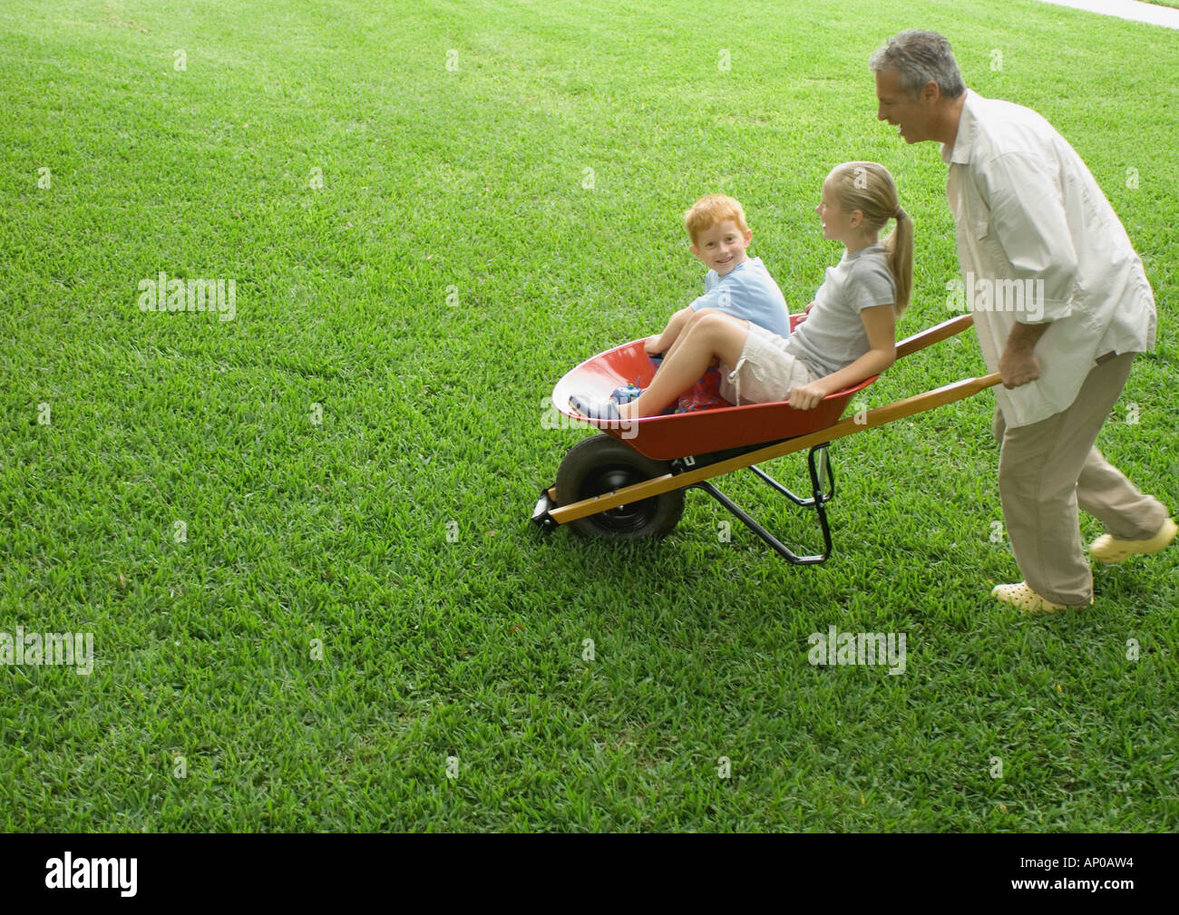 Man pushing two children in wheelbarrow Stock Photo - Alamy