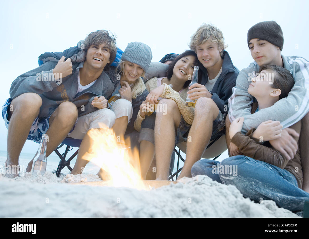 Group of friends sitting around campfire Stock Photo - Alamy