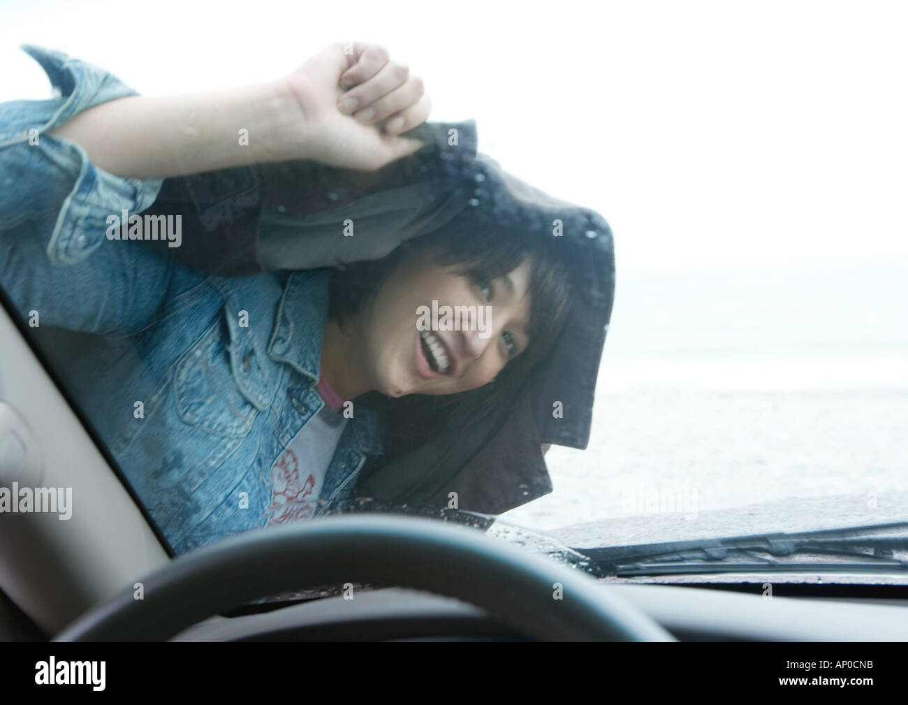 Woman looking through windshield, holding jacket over head Stock Photo ...