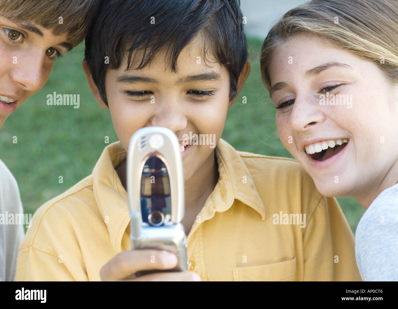 Three preteen kids looking at cell phone Stock Photo - Alamy