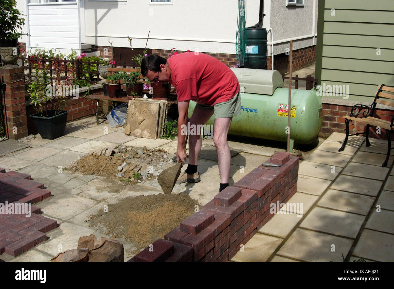An male construction worker mixing cement by hand at a building site ...