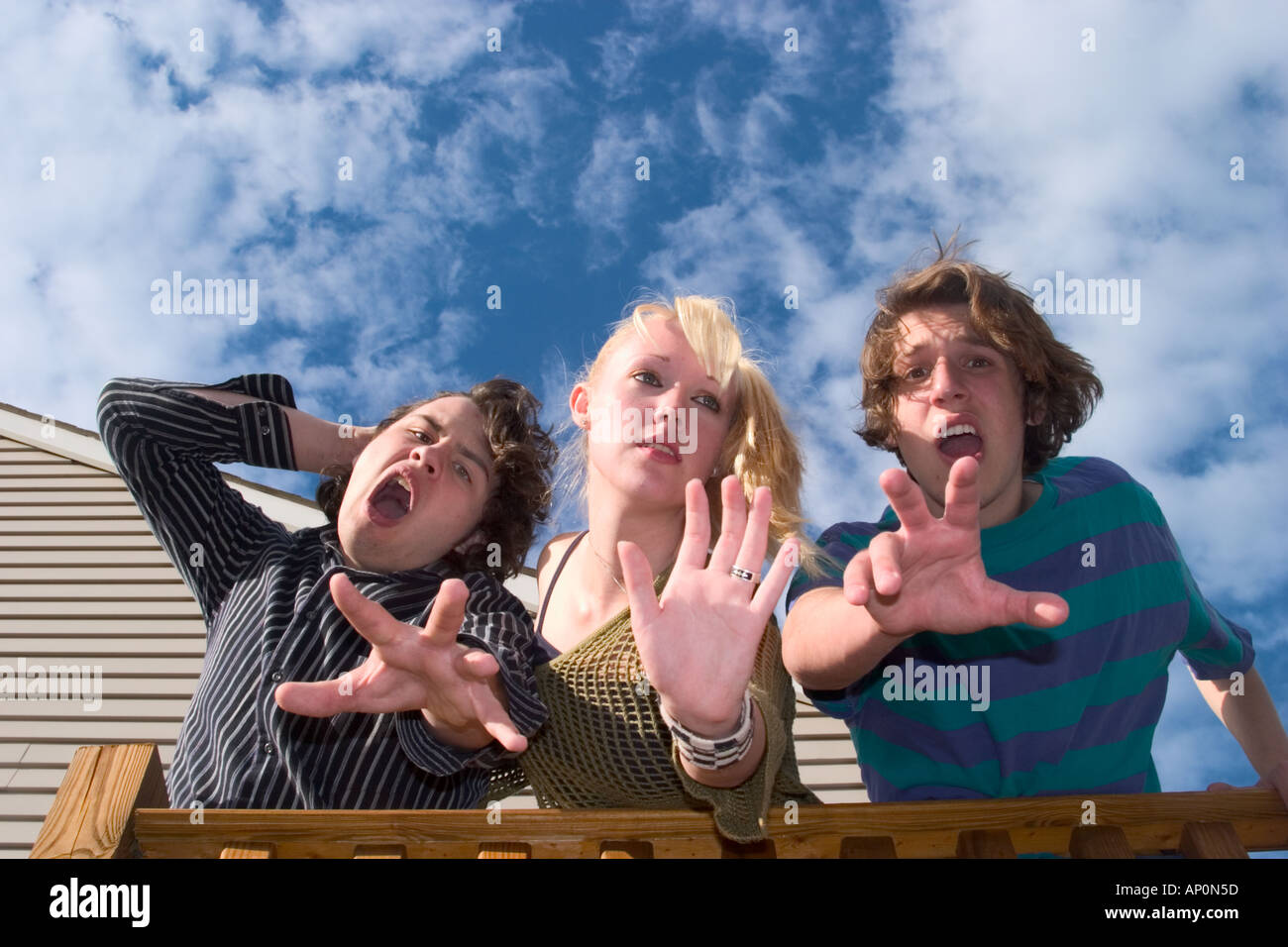 Teen boys and a teen girl standing together on a porch frantically ...