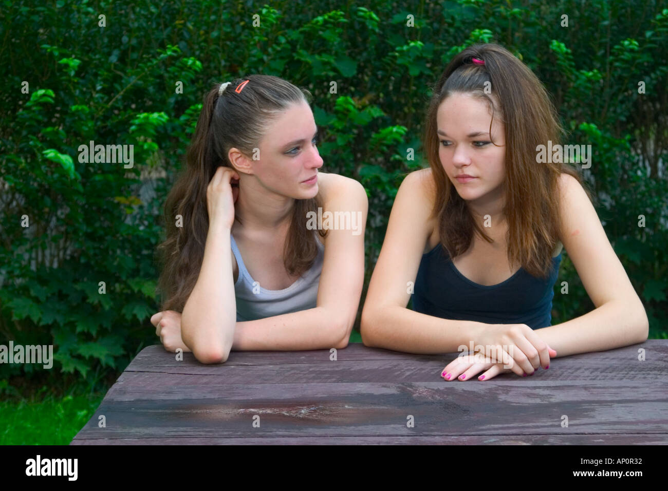 Teen sisters sitting and talking together at a picnic table Model ...
