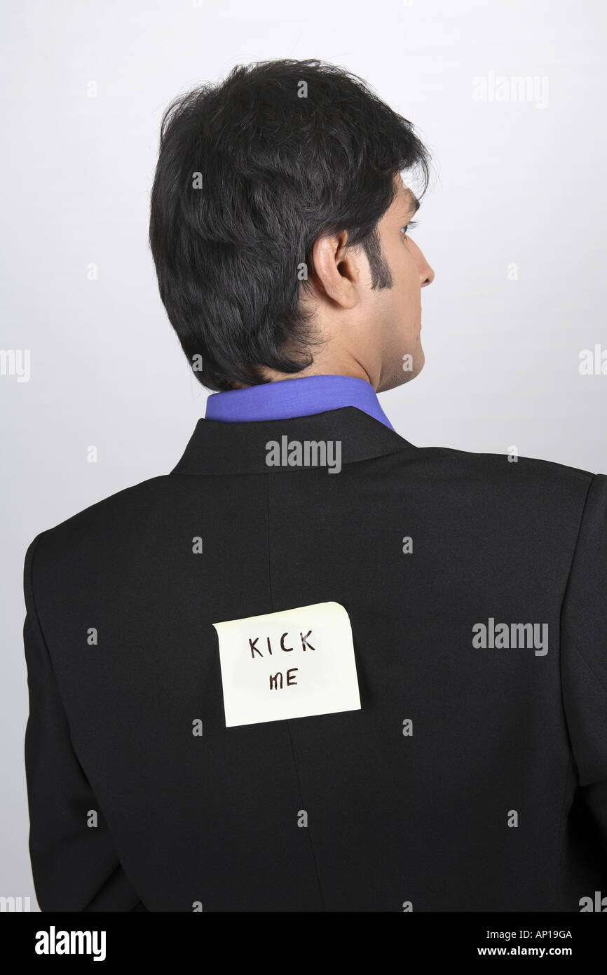 ANG200091 Executive with the paper label sticker of kick me on his back ...