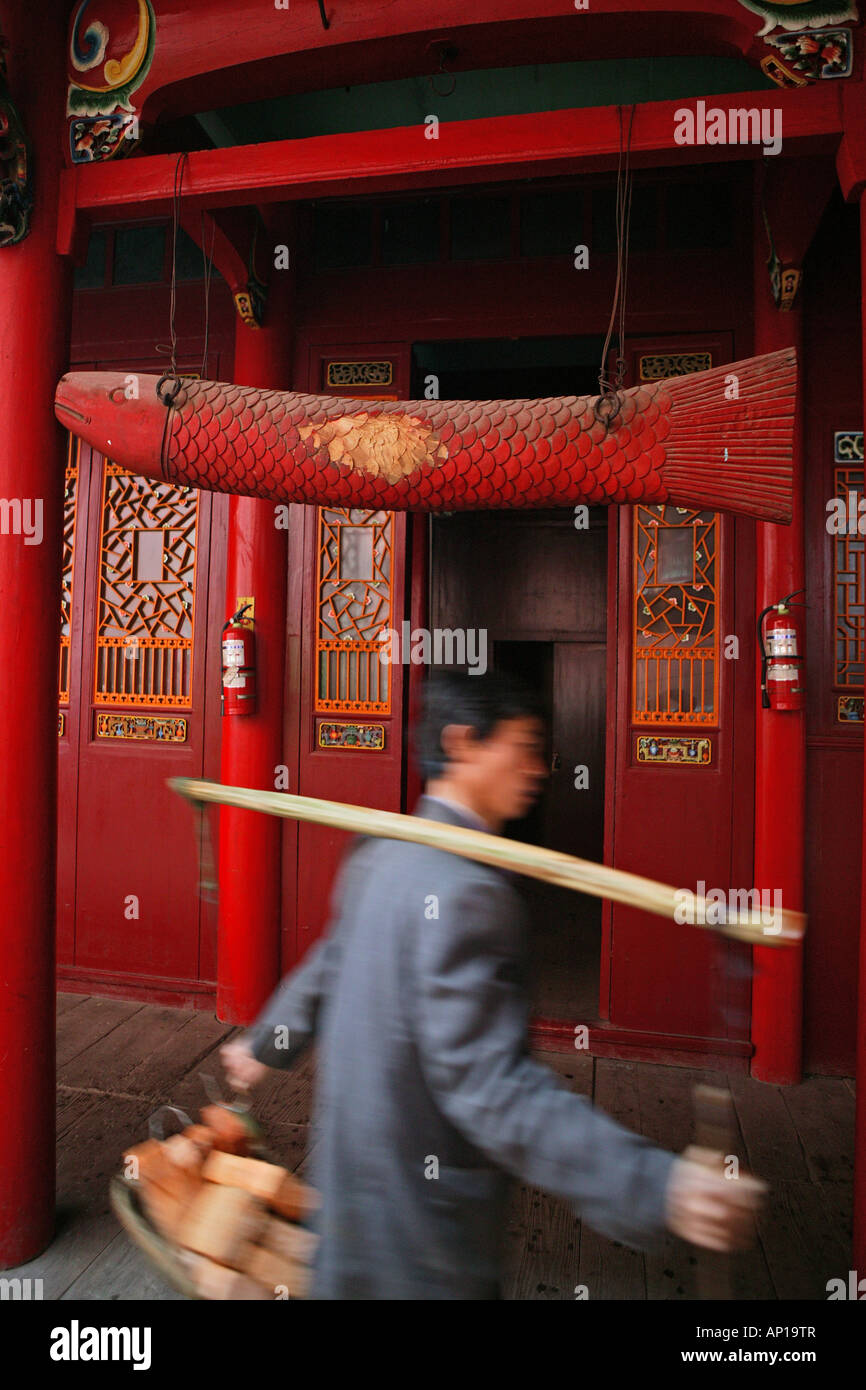 Porter with building material and wooden fish in front of Qiyuan ...