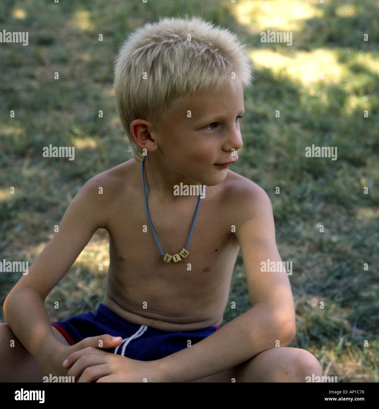 fair haired Boy sitting on a meadow Stock Photo - Alamy