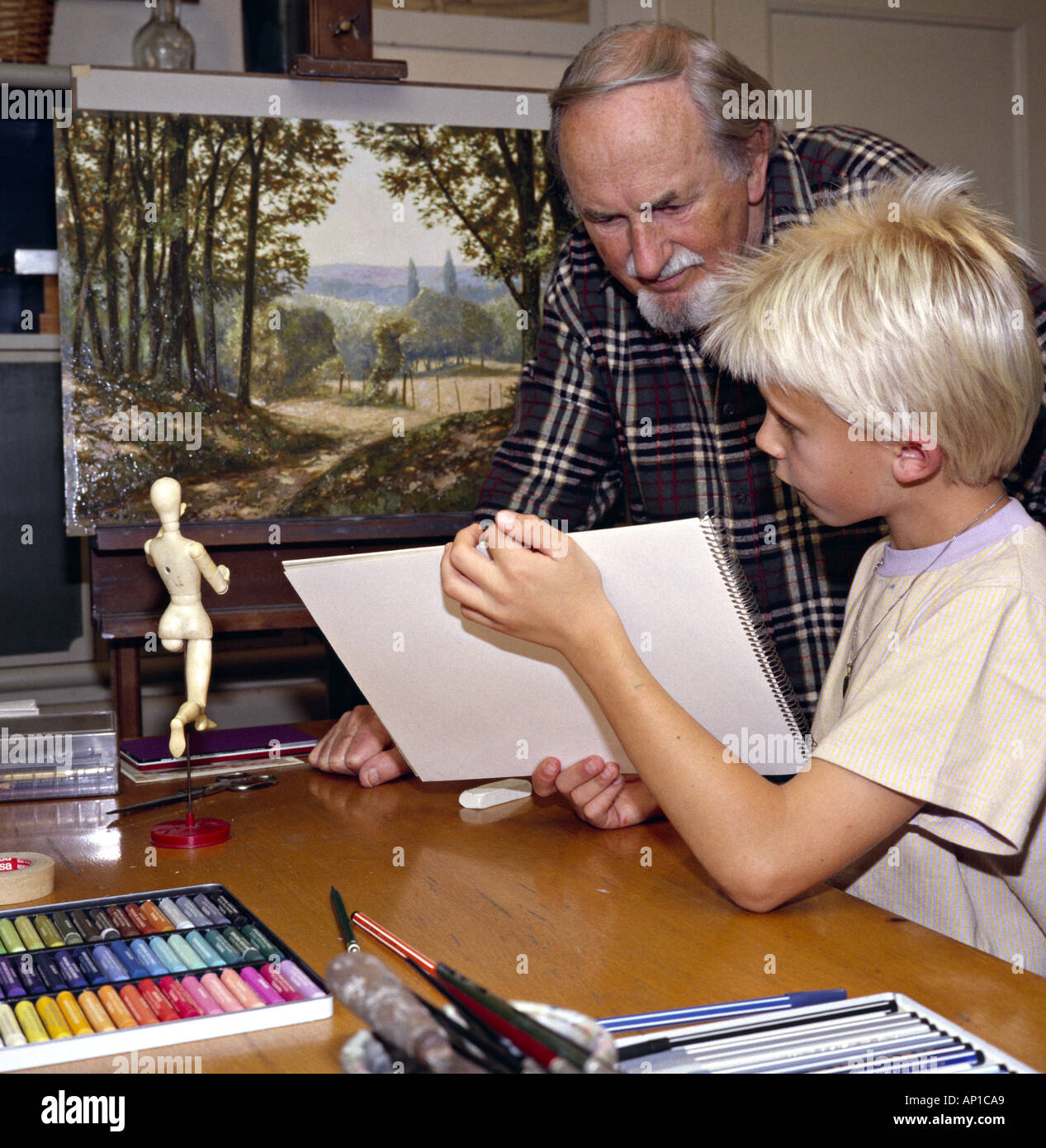 elder man teaching a fair haired boy to draw Stock Photo - Alamy