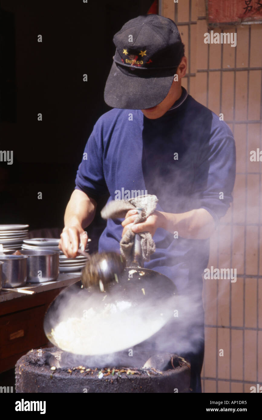 Local man wearing baseball cap cooking food in steaming wok hi-res ...