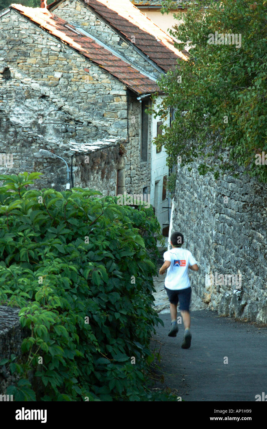 Boy running down alleyway in French village Stock Photo - Alamy