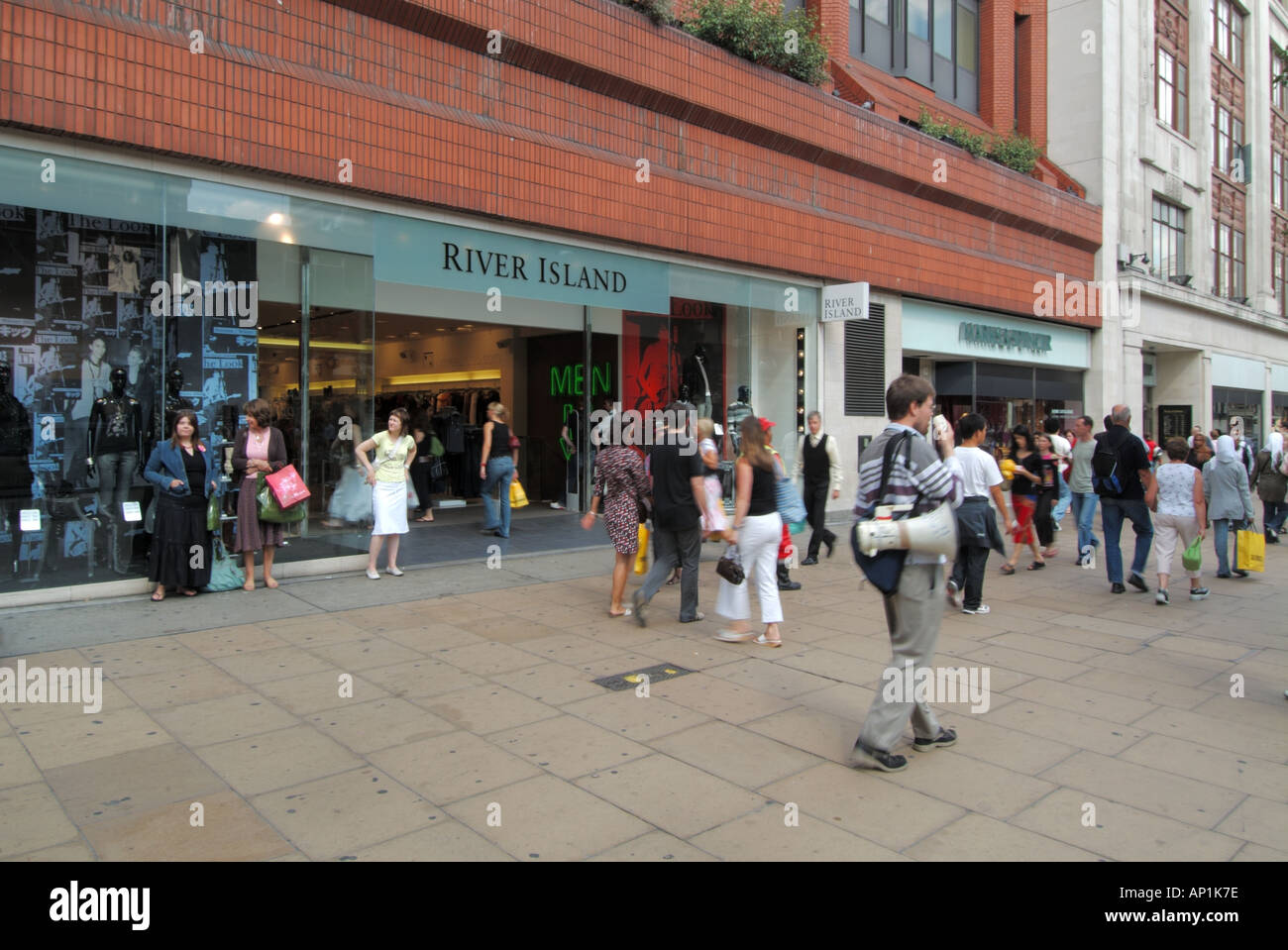 Shoppers on pavement outside store windows River Island clothing shop ...