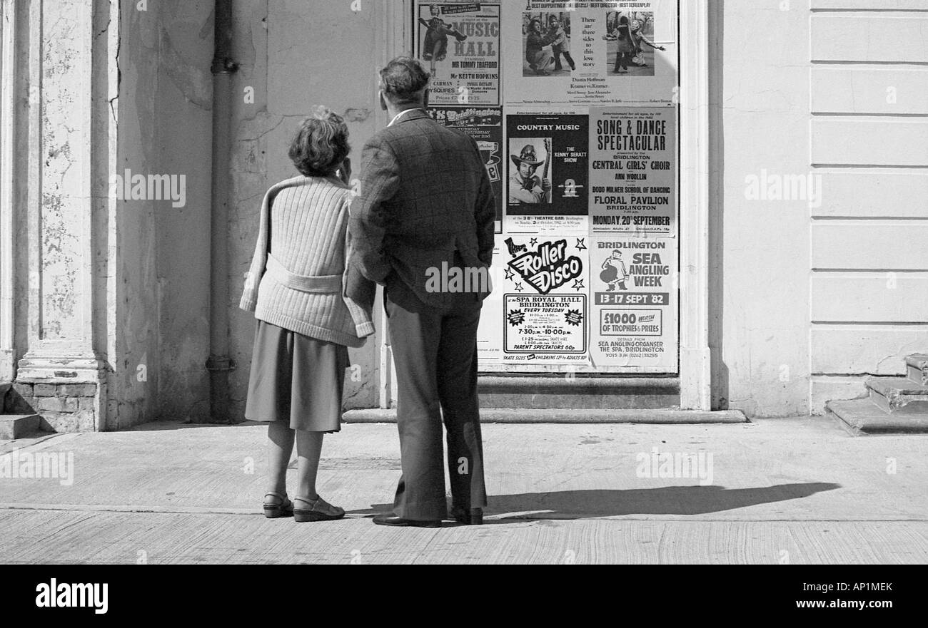Two people looking at list of performances outside a seaside theatre ...