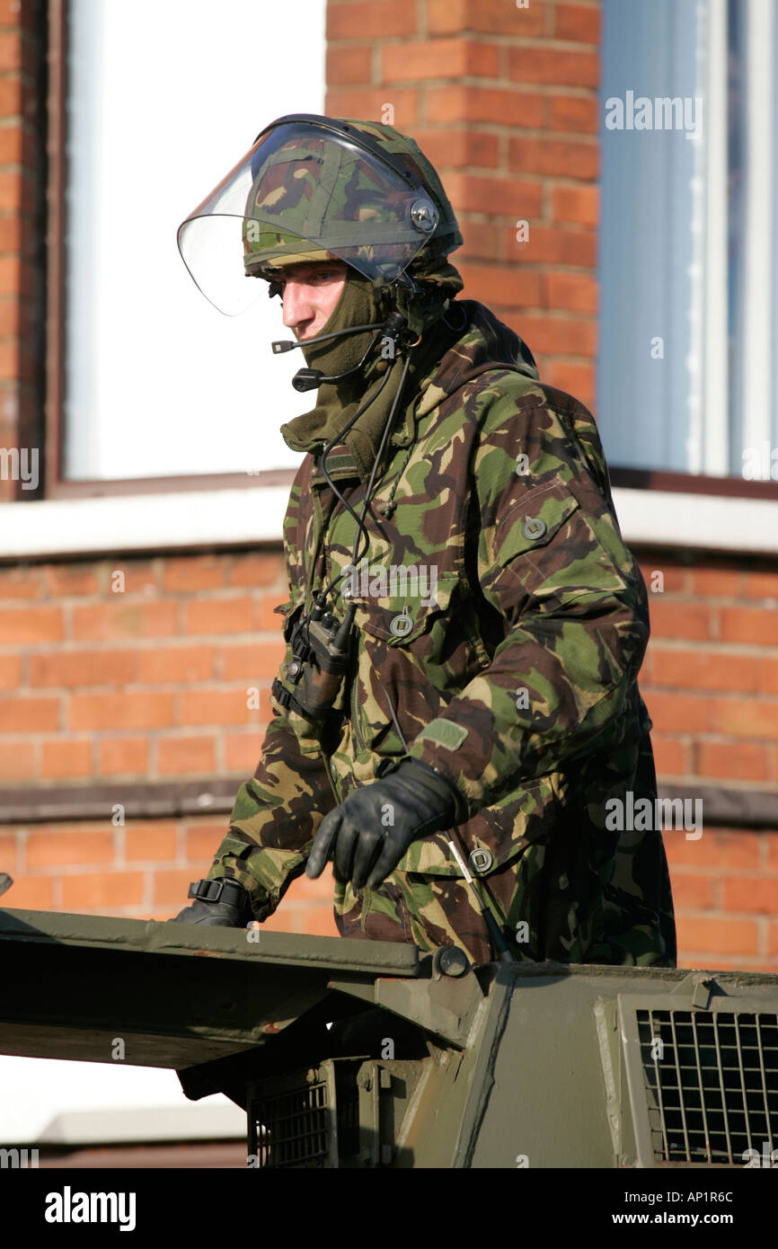 British Army soldier in turret of Saxon Vehicle in front of houses on ...