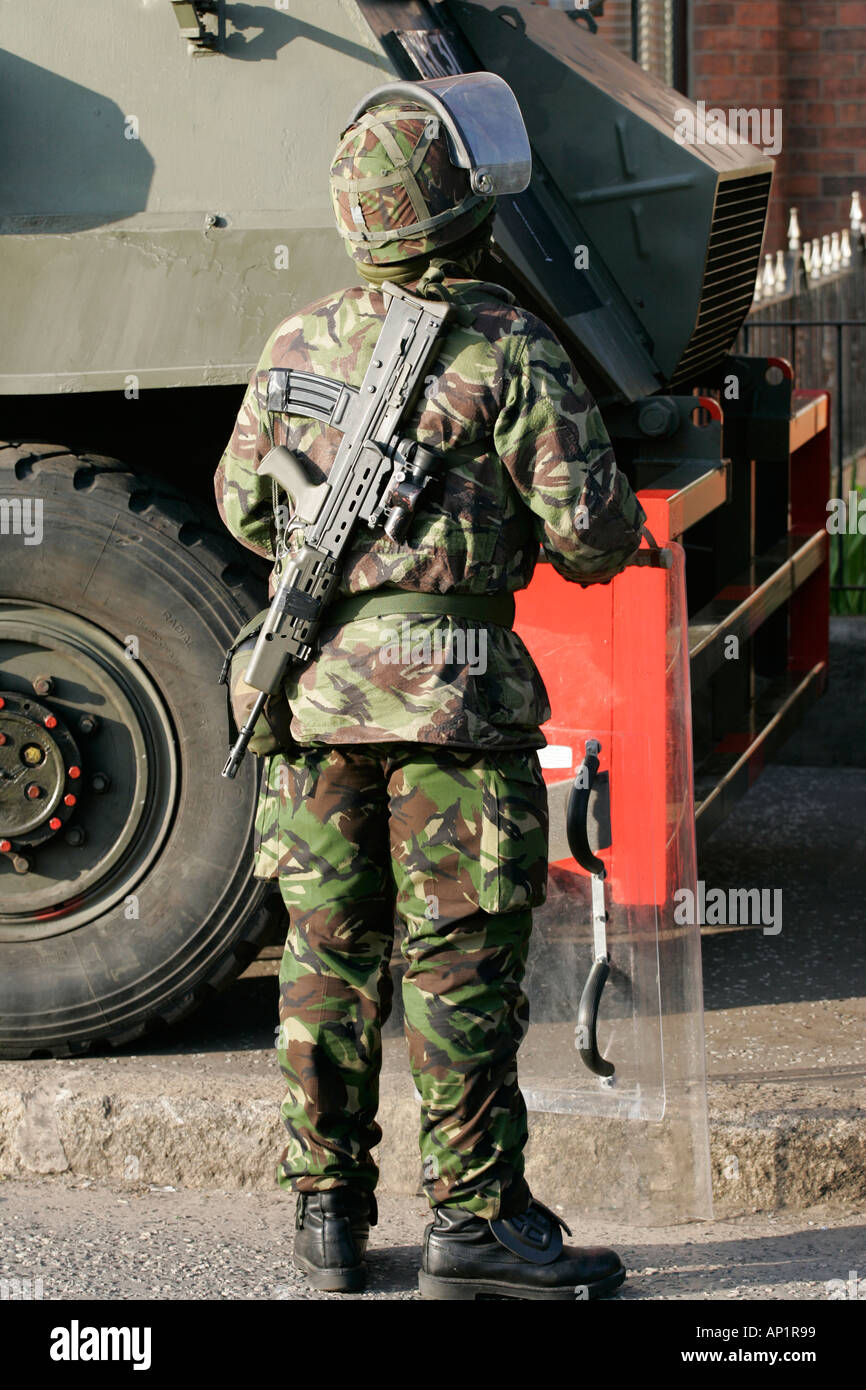British army soldier in riot gear with SA80 in front of Saxon vehicle ...