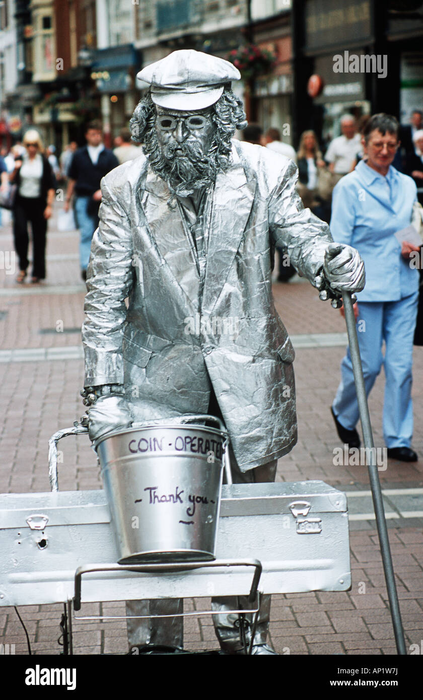 Man dressed in silver clothing and coated in silver paint, pushing ...